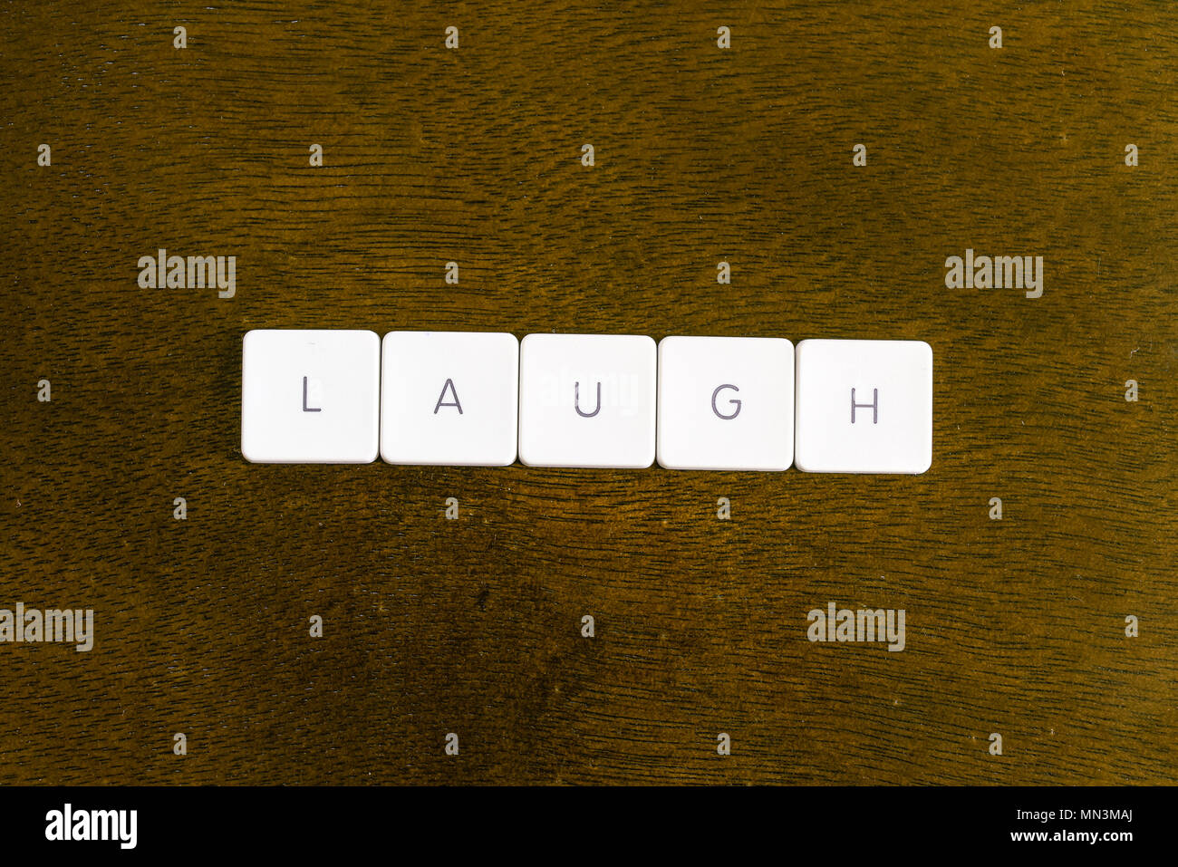 LAUGH word written on plastic keyboard alphabet with dark background ...
