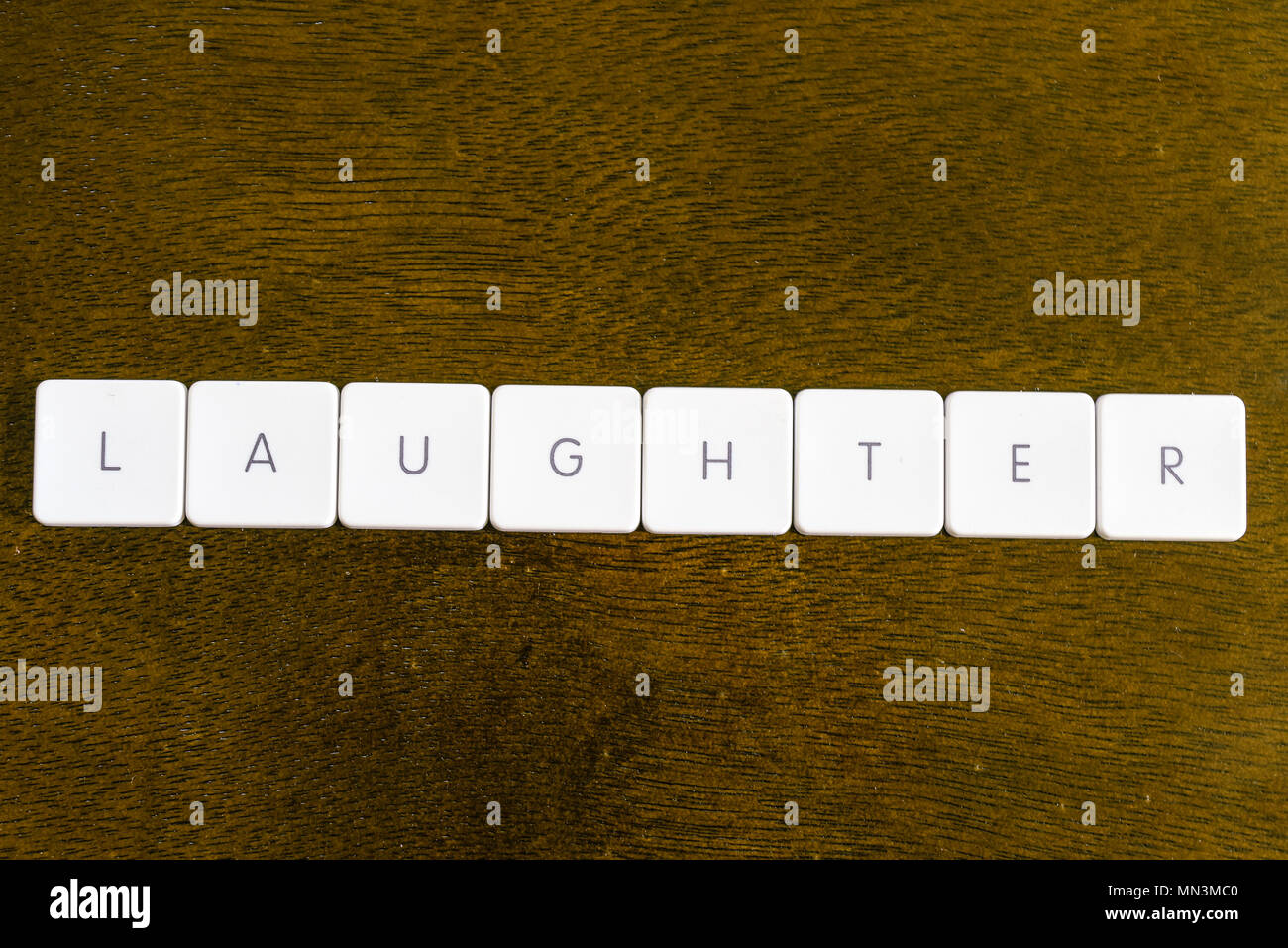 LAUGHTER word written on plastic keyboard alphabet with dark background ...