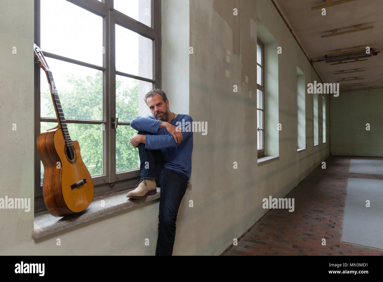 musician sitting next to a window with a classical guitar Stock Photo ...