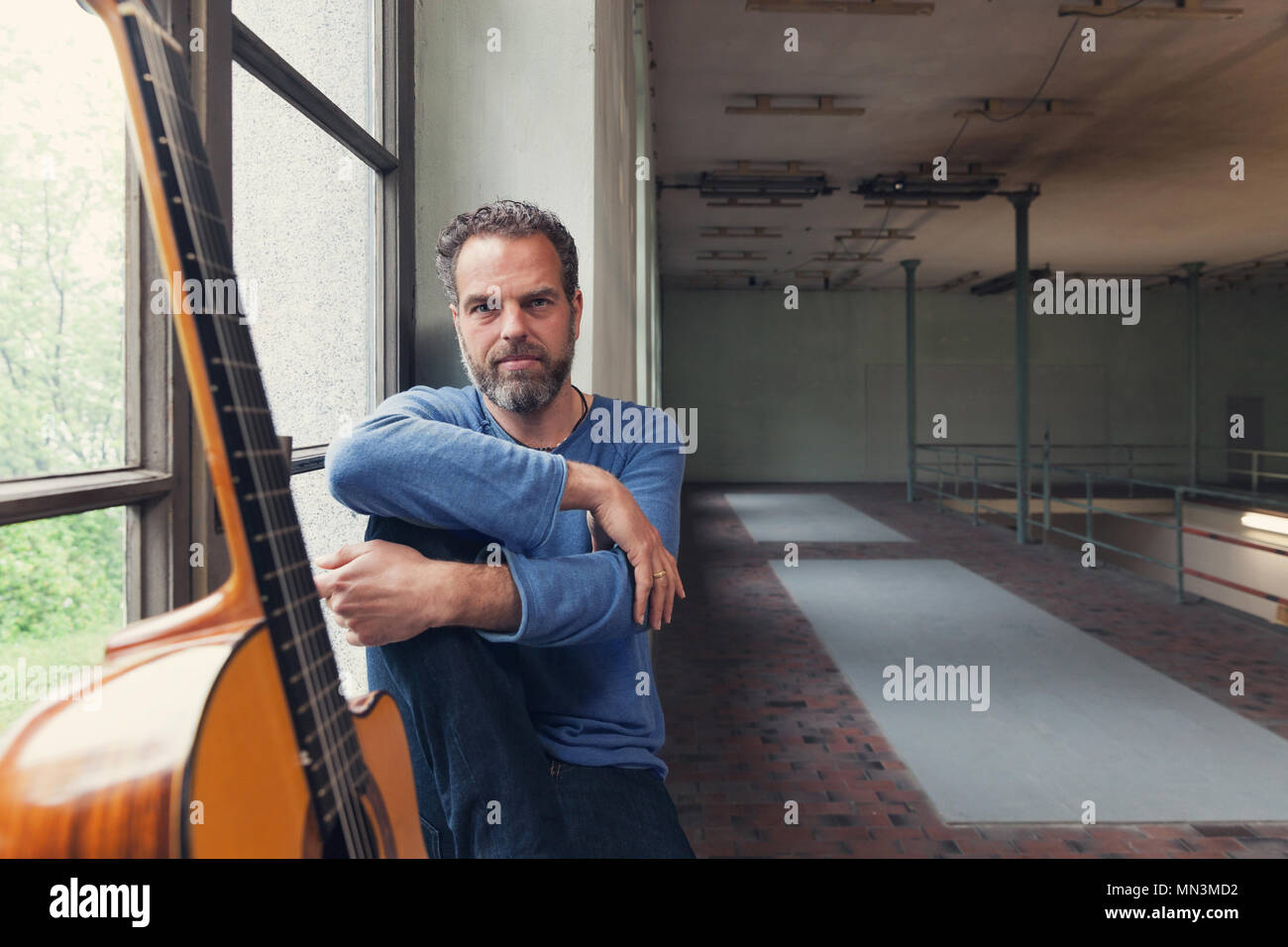 musician sitting next to a window with a classical guitar Stock Photo ...