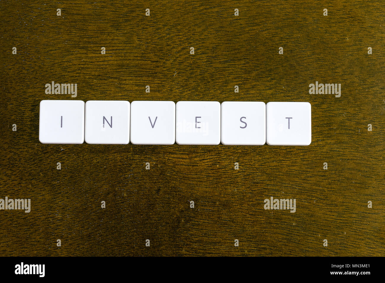 INVEST word written on plastic keyboard alphabet with dark background ...