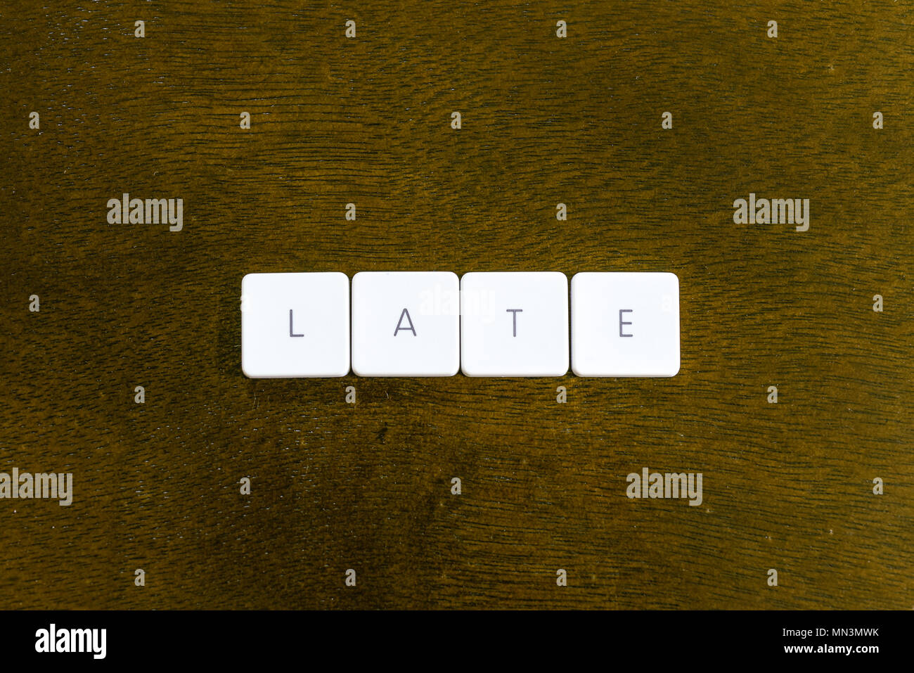LATE word written on plastic keyboard alphabet with dark background ...