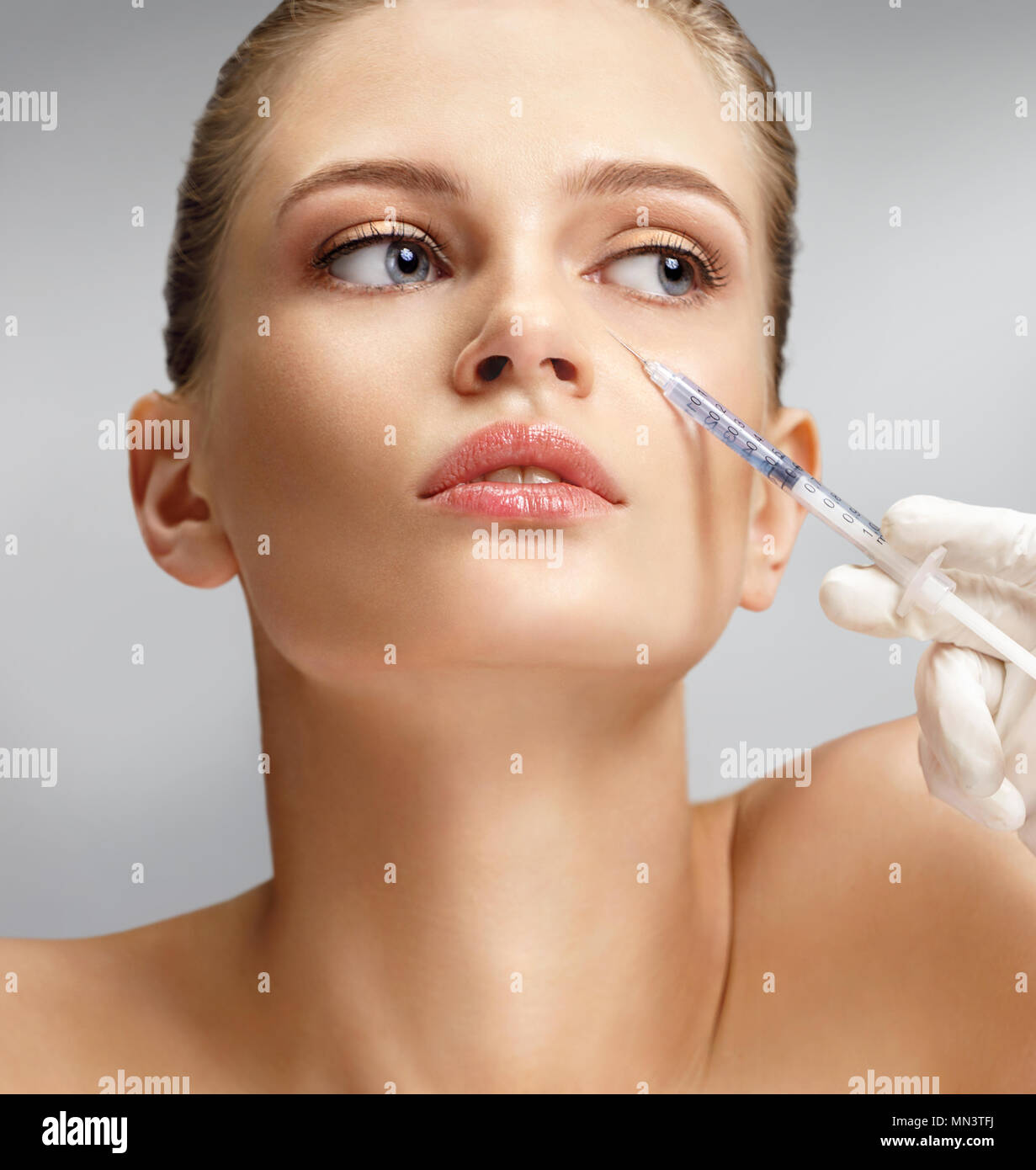 Beautiful woman getting cosmetic injection in eye area from beautician ...