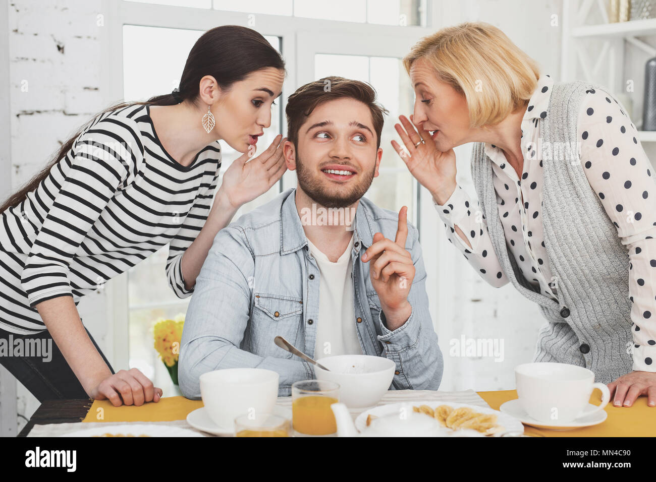 Joyful nice man being in between his wife and mother Stock Photo - Alamy