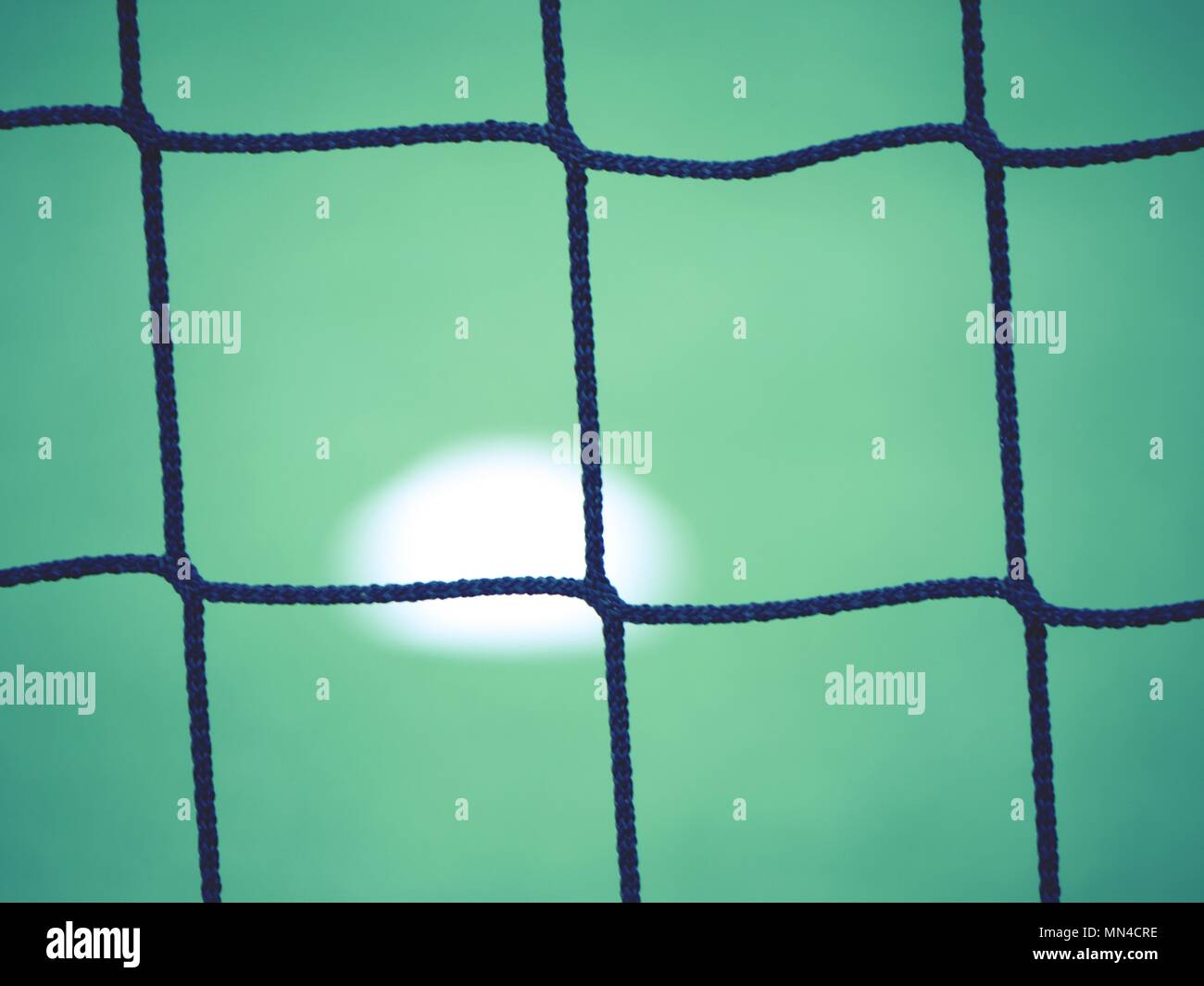 View through football gate net. Soccer ball on green grass viewed ...