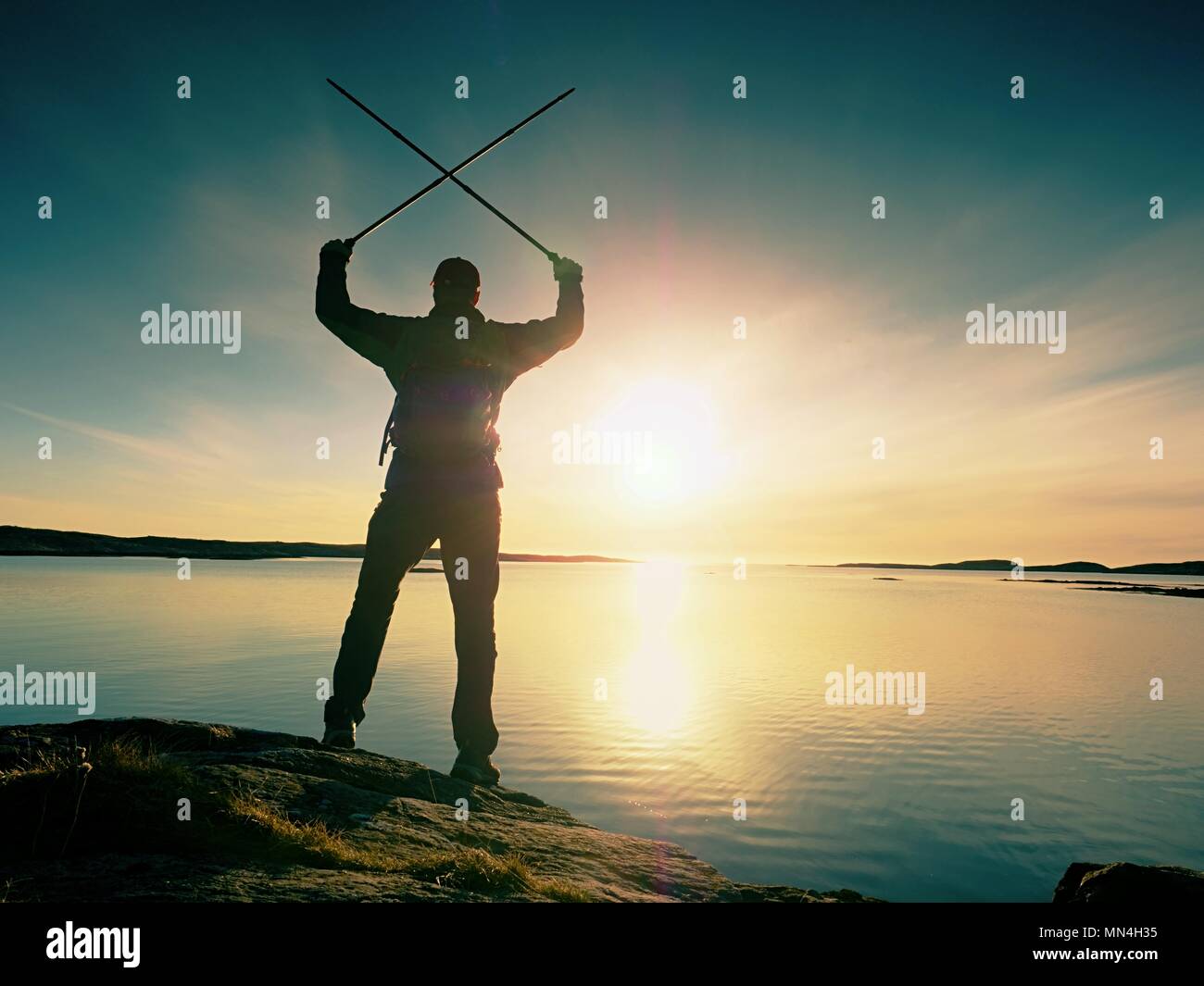 Man, sea and sun at horizon. Traveler on rocky cliff above sea enjoy ...