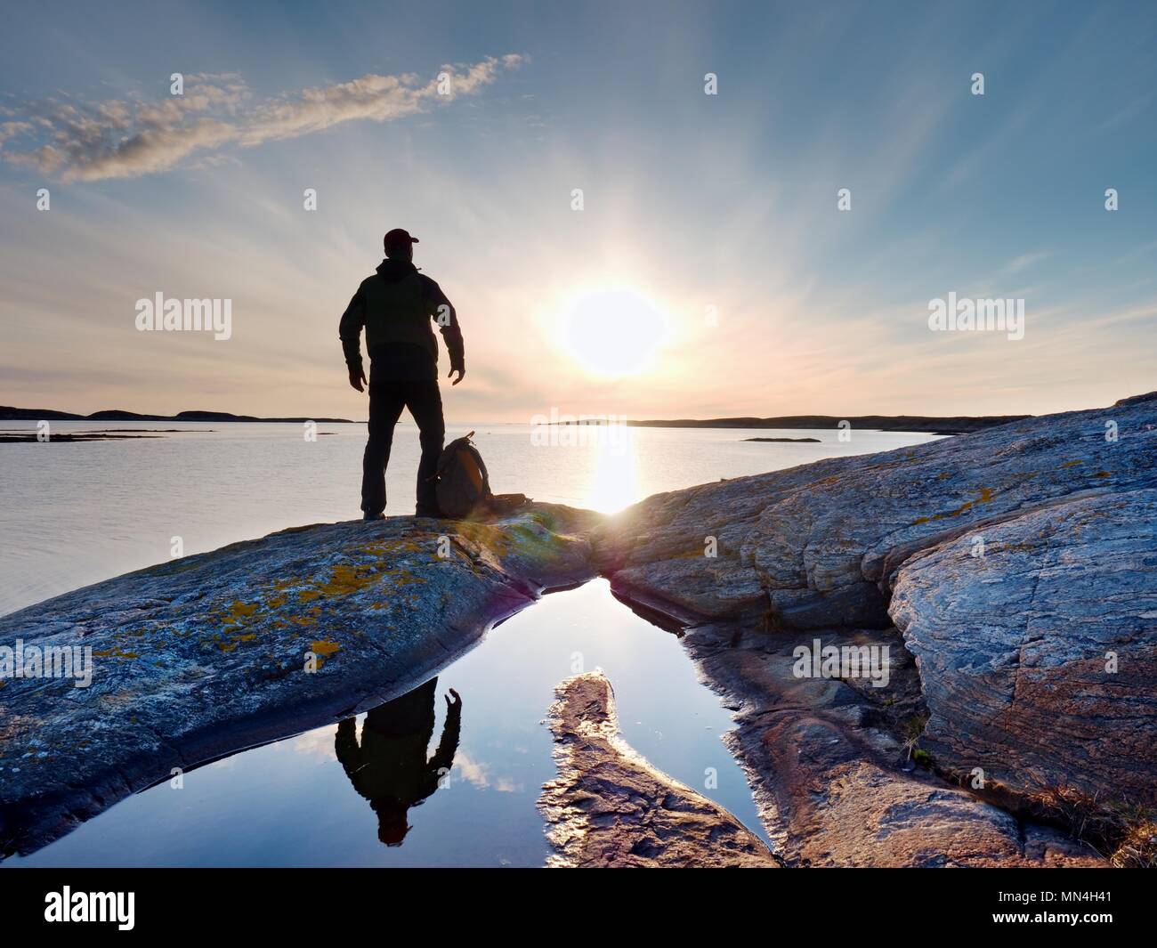 Silhouette of alone man looking toward vibrant sunset. Flare and ...