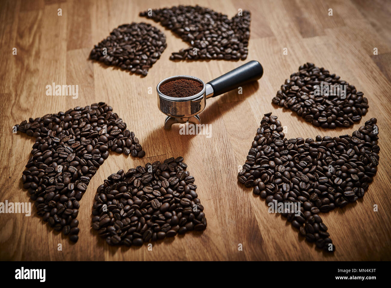 Coffee beans forming recycle symbol around espresso grounds in ...