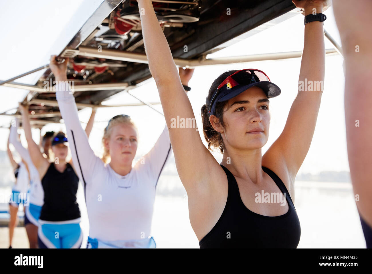 Confident, determined female rowing team lifting scull overhead Stock ...