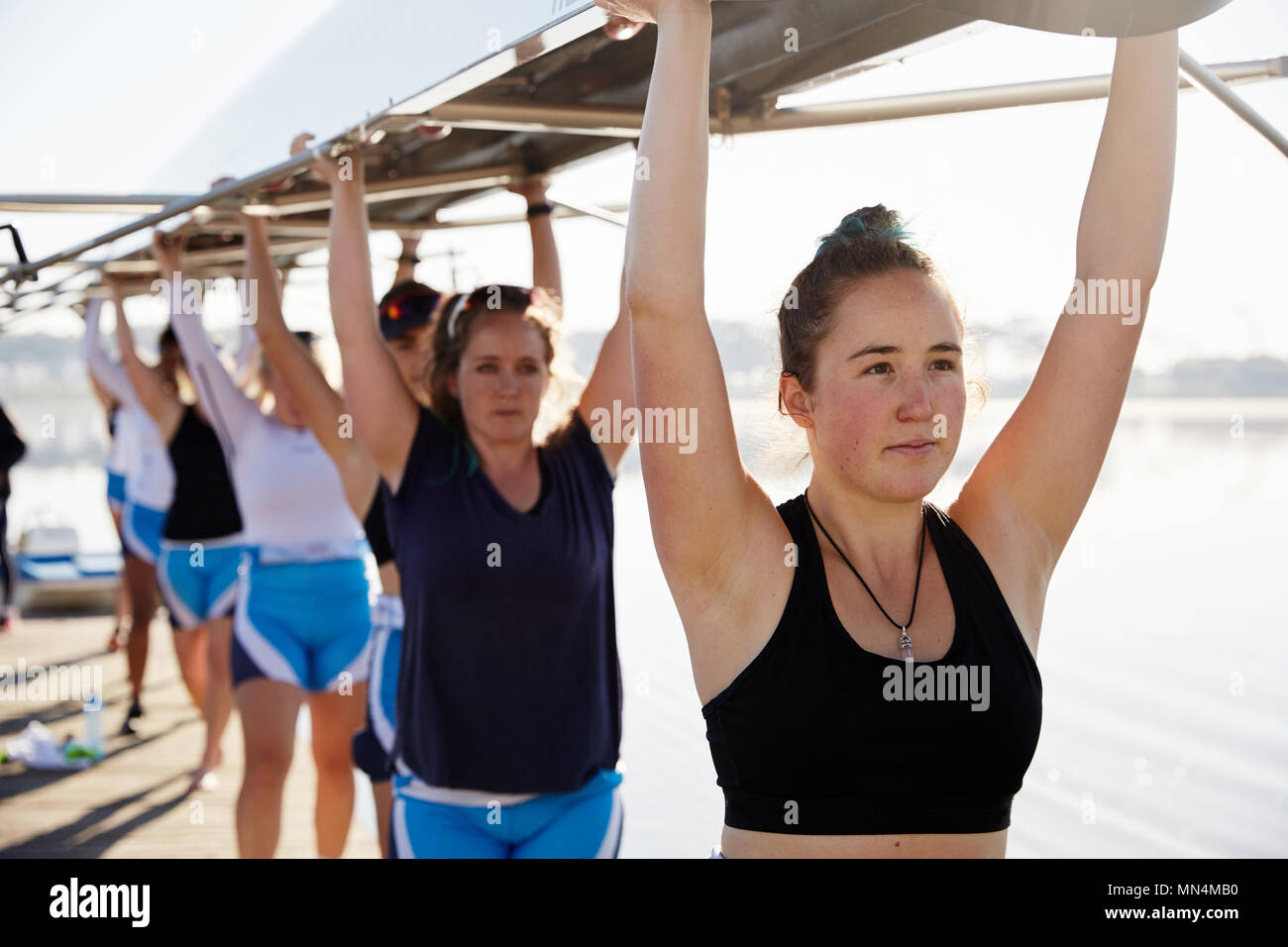 Confident, determined female rowing team lifting scull overhead Stock ...