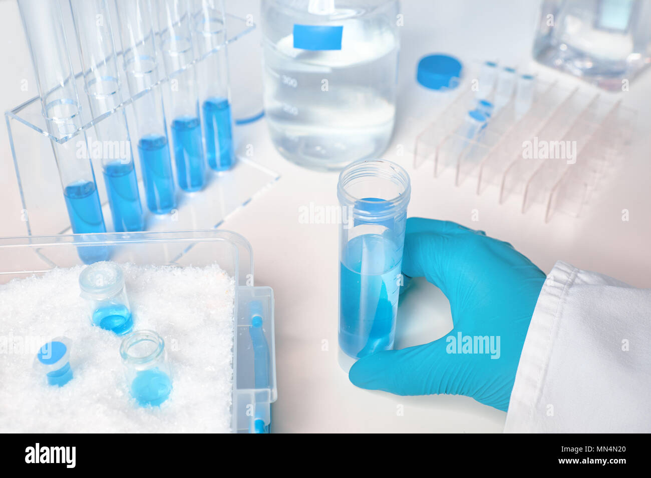 Scientific background in white and blue. Liquid sample in gloved female ...