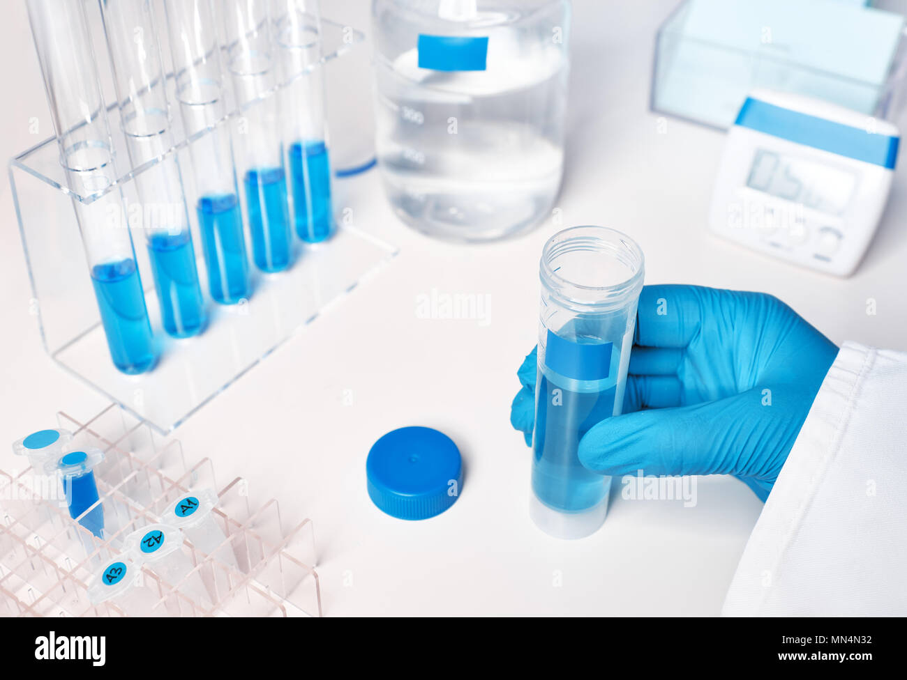 Scientific background in white and blue. Liquid sample in gloved female ...