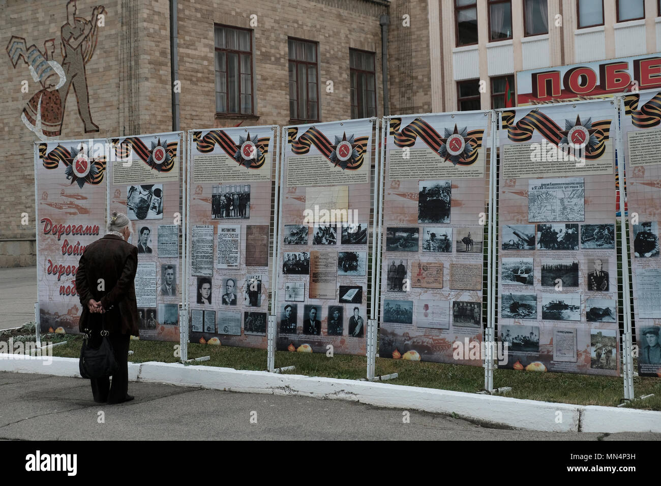 An elderly Transnistrian woman stands next to stands with old ...