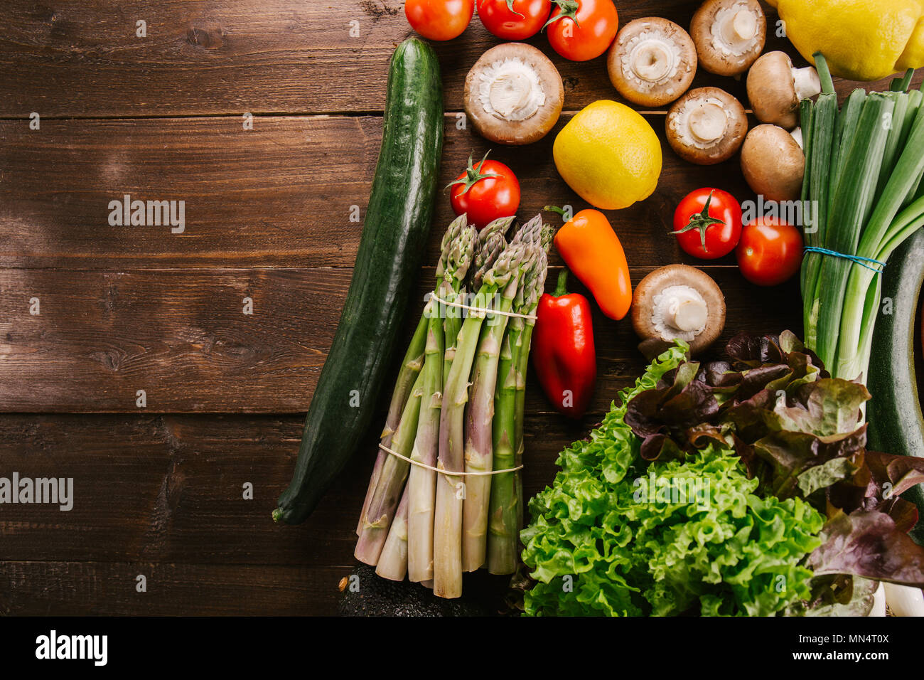 Top view of wooden table with healthy green vegetables arranged in pile ...