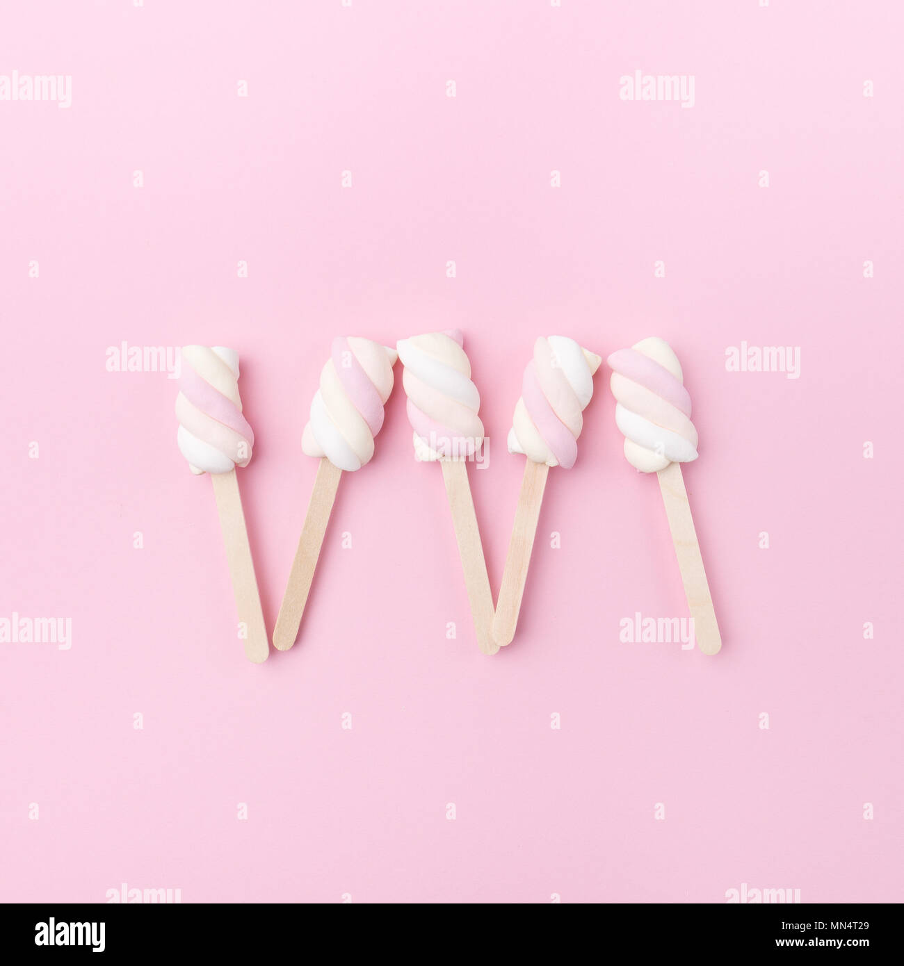 Different pastel color marshmallows on sticks on pink pastel background ...