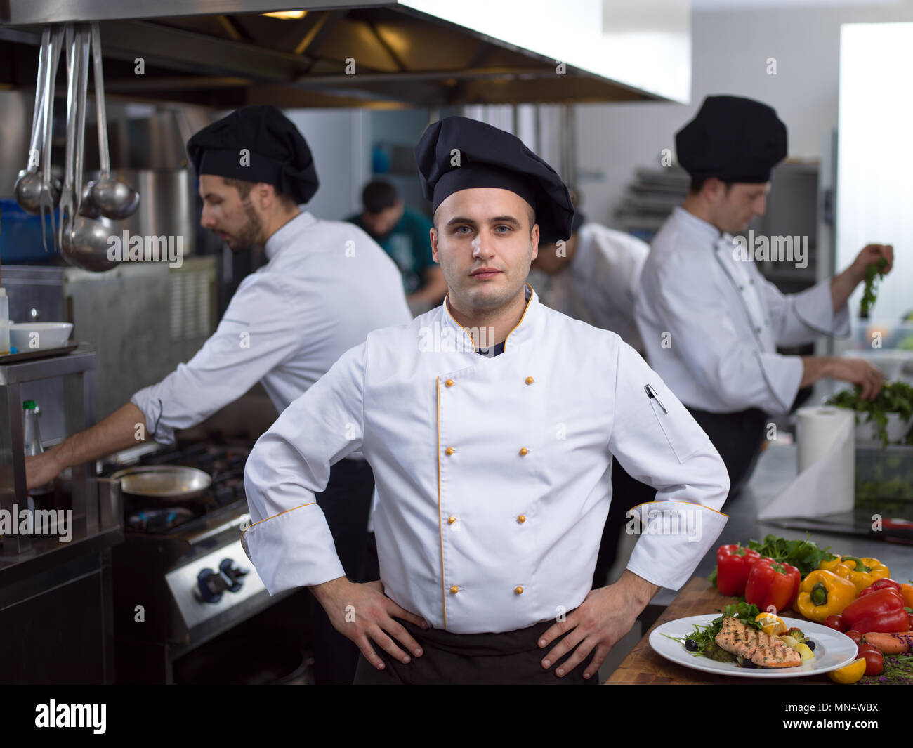 Portrait of young chef standing in commercial kitchen at restaurant ...