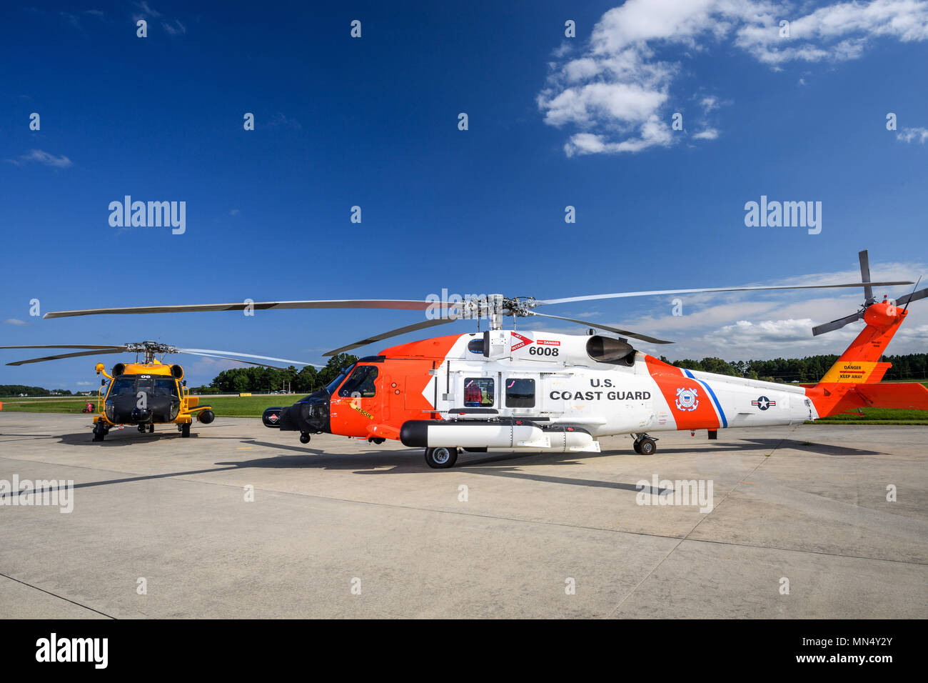 Two Coast Guard MH-60 Jayhawk helicopters sit at the ramp outside the ...