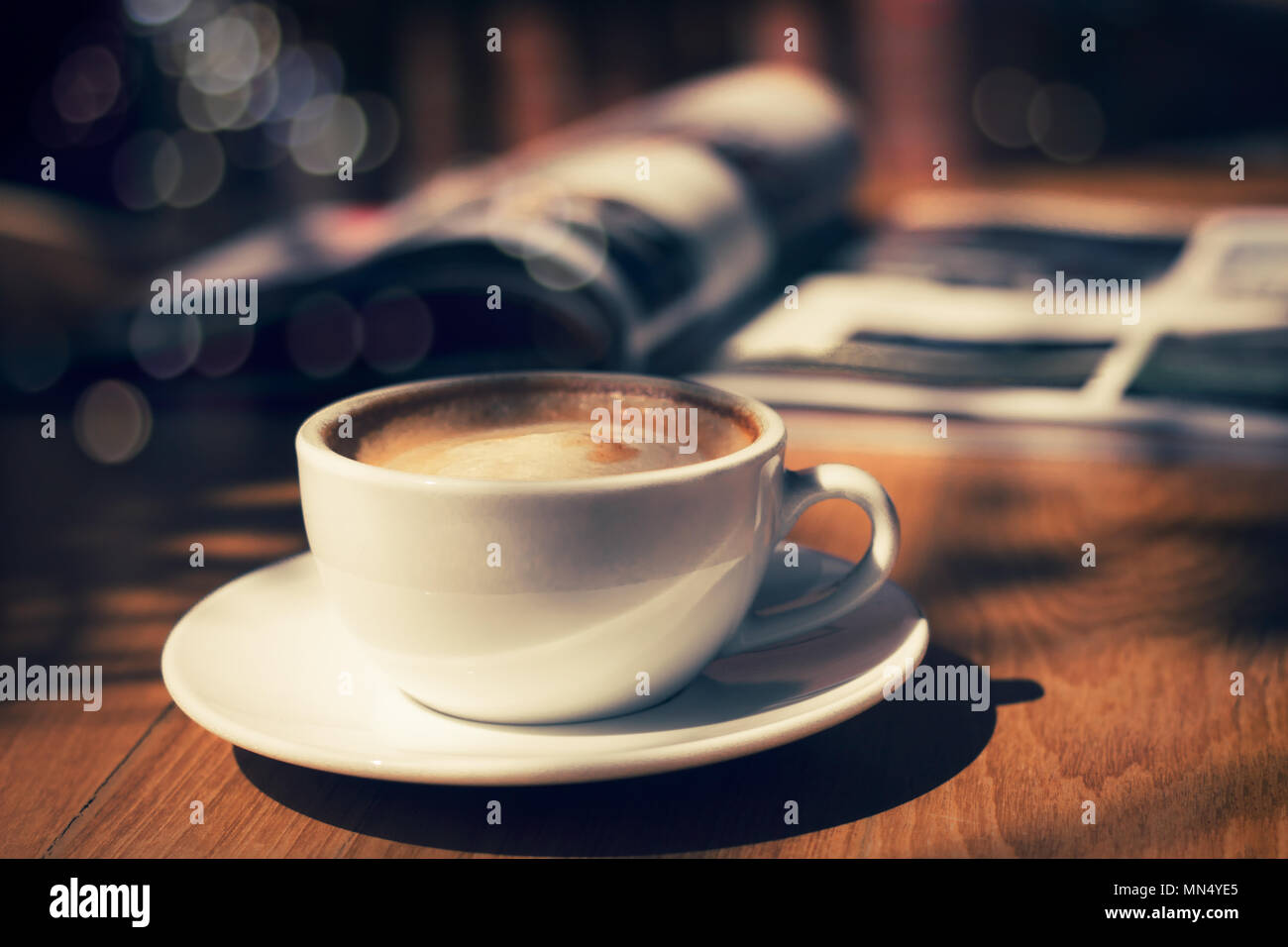 cup of coffee with magazine on table in cafe in dark tone and vintage ...