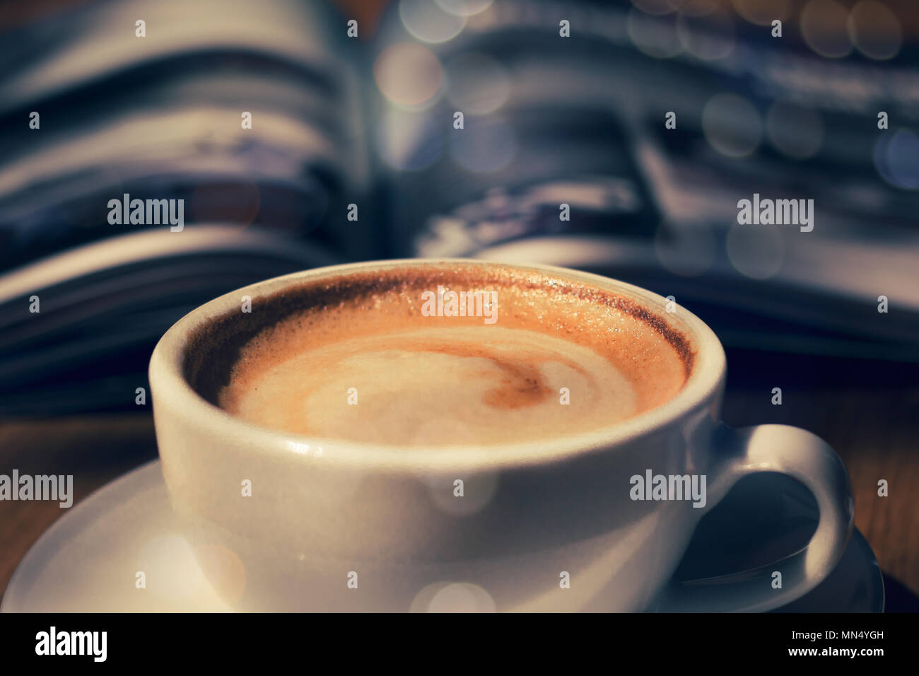 cup of coffee with magazine on table in cafe in dark tone and vintage ...