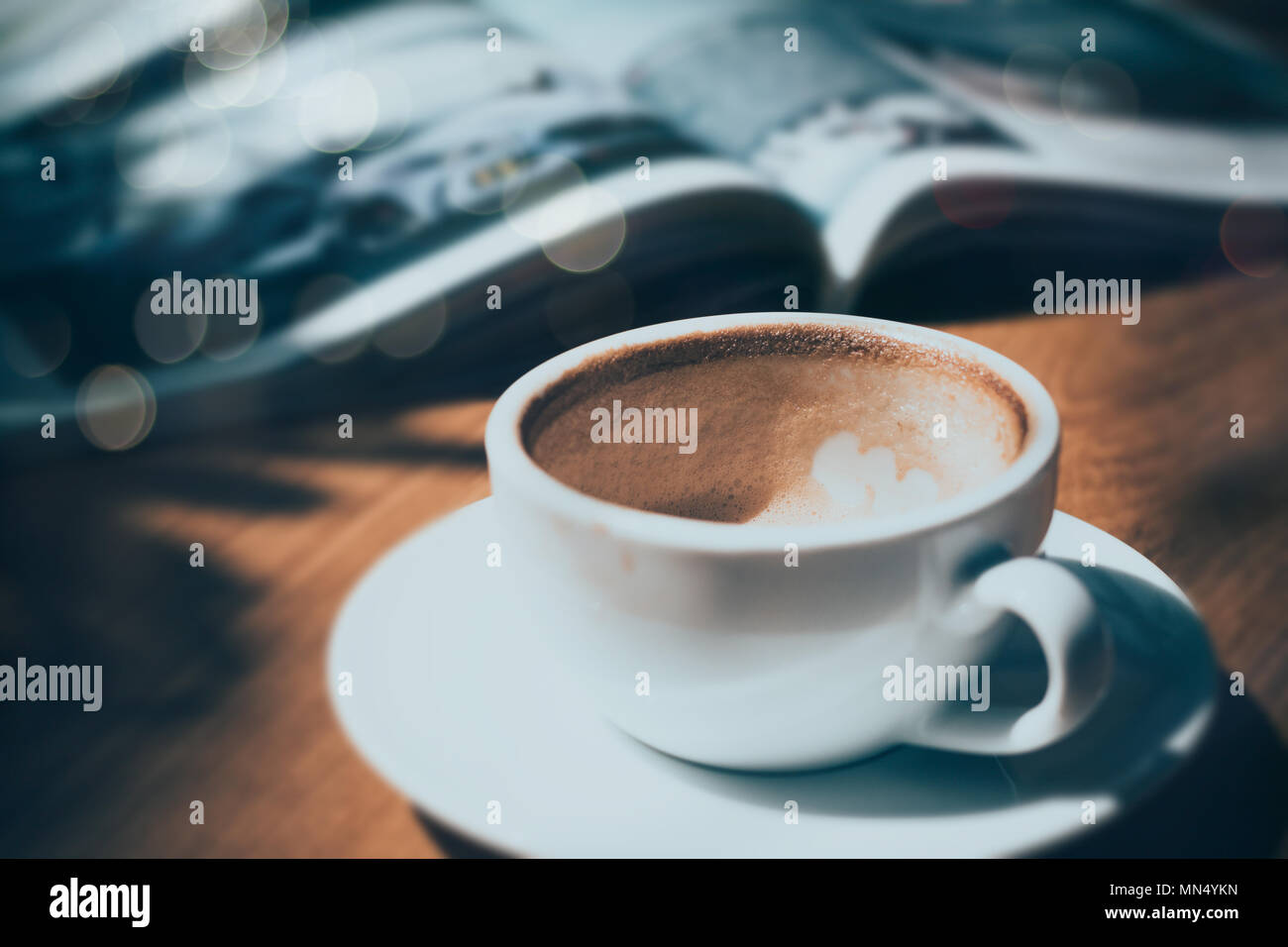 cup of coffee with magazine on table in cafe in dark tone and vintage ...