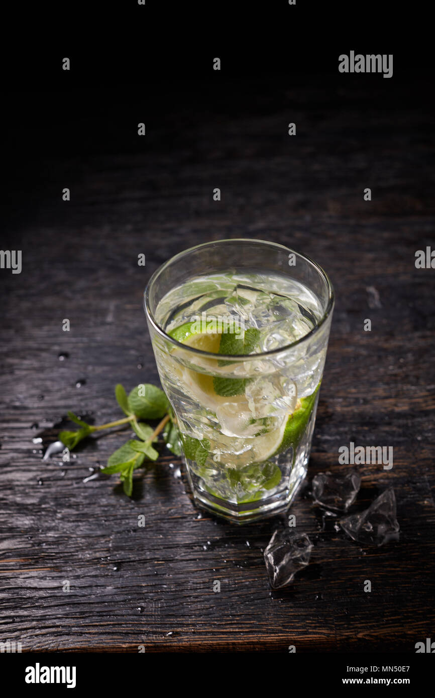 From above shot of mojito cocktail with ice and mint in glass on dark ...