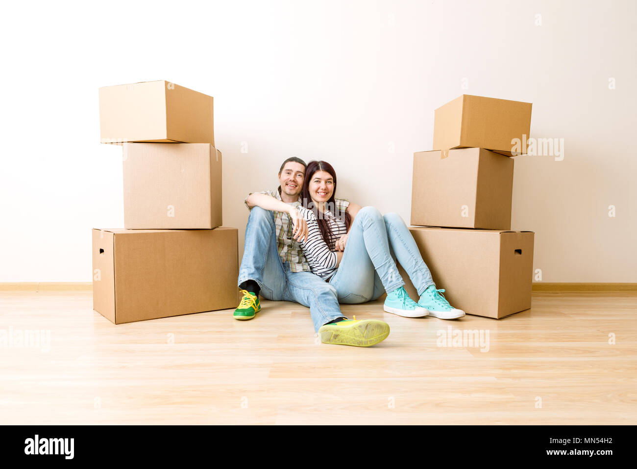 Photo of young couple sitting on floor among cardboard boxes Stock ...