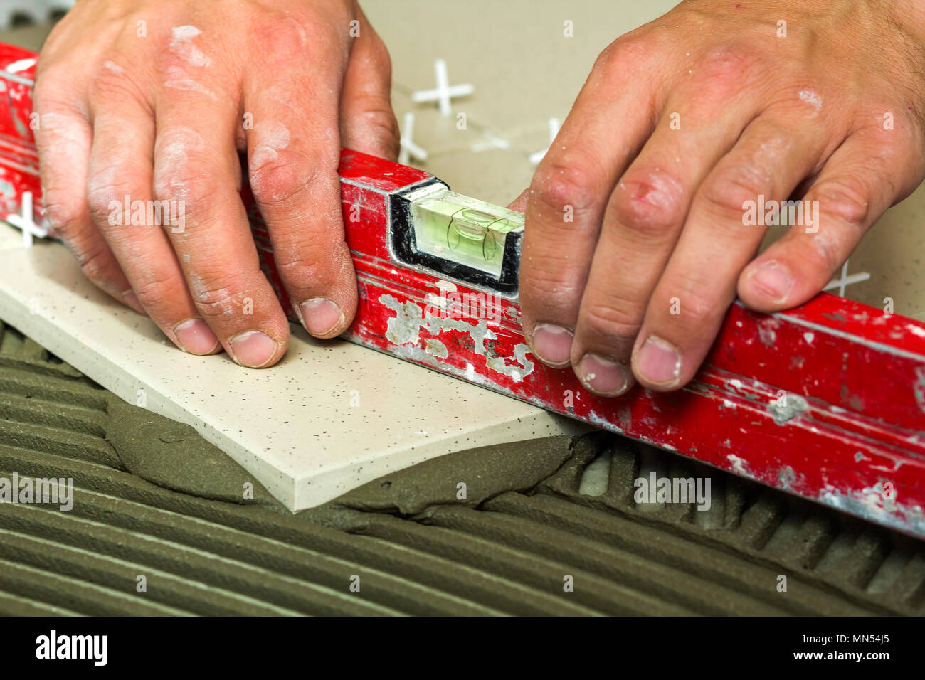 Ceramic tiles and tools for tiler. Worker hand installing floor tiles ...