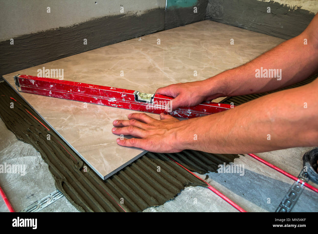 Ceramic tiles and tools for tiler. Worker hand installing floor tiles ...