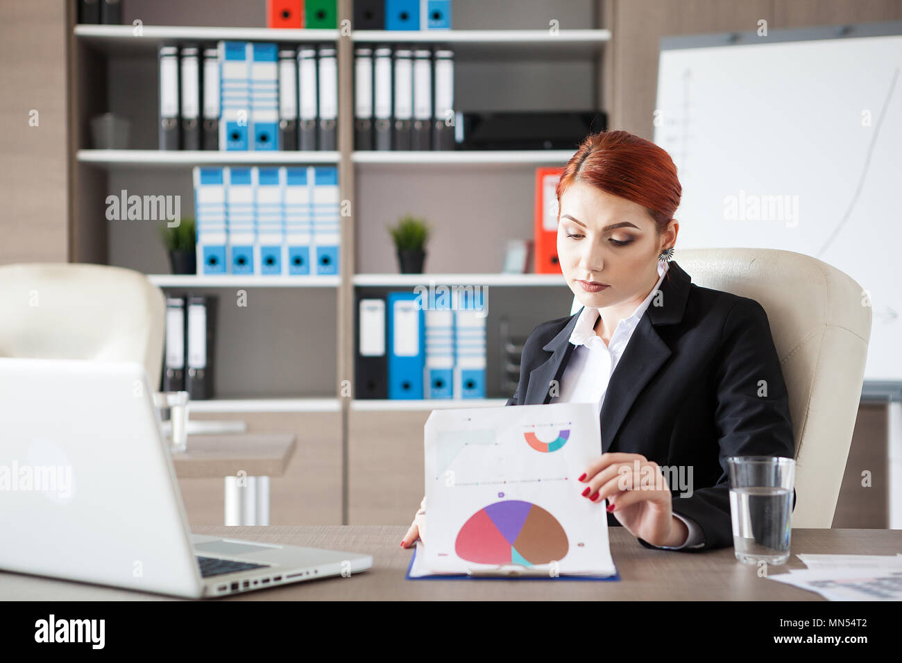 Businesswoman in her office checking documents with diagrams on them ...