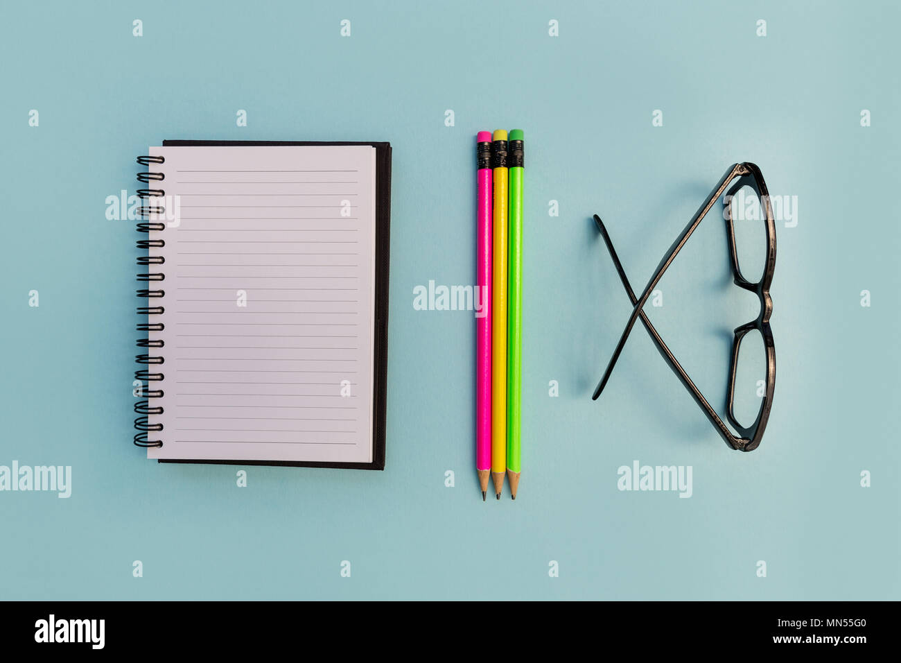 Education notebook pencil and eyeglasses on bright blue background ...
