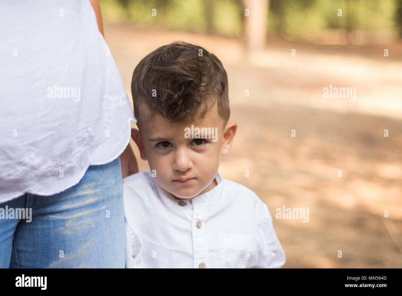Shy boy standing with his mother outdoors Stock Photo - Alamy