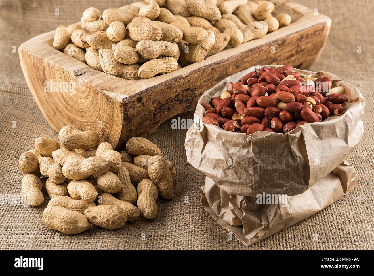 Paper bag full of peeled peanuts and peanuts in nutshell on a piece of ...