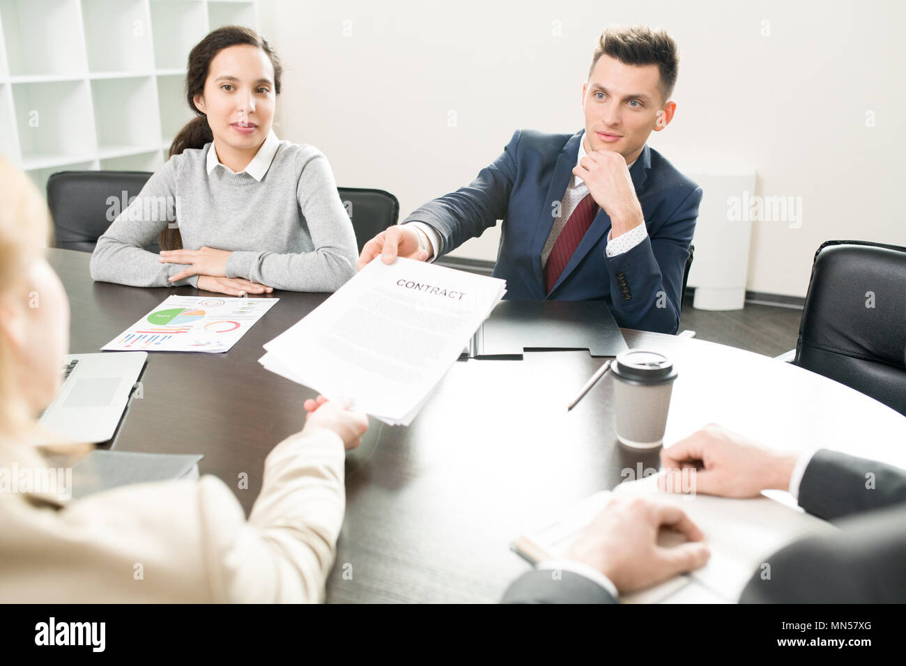 Portrait of handsome businessman handing contract to partner and ...
