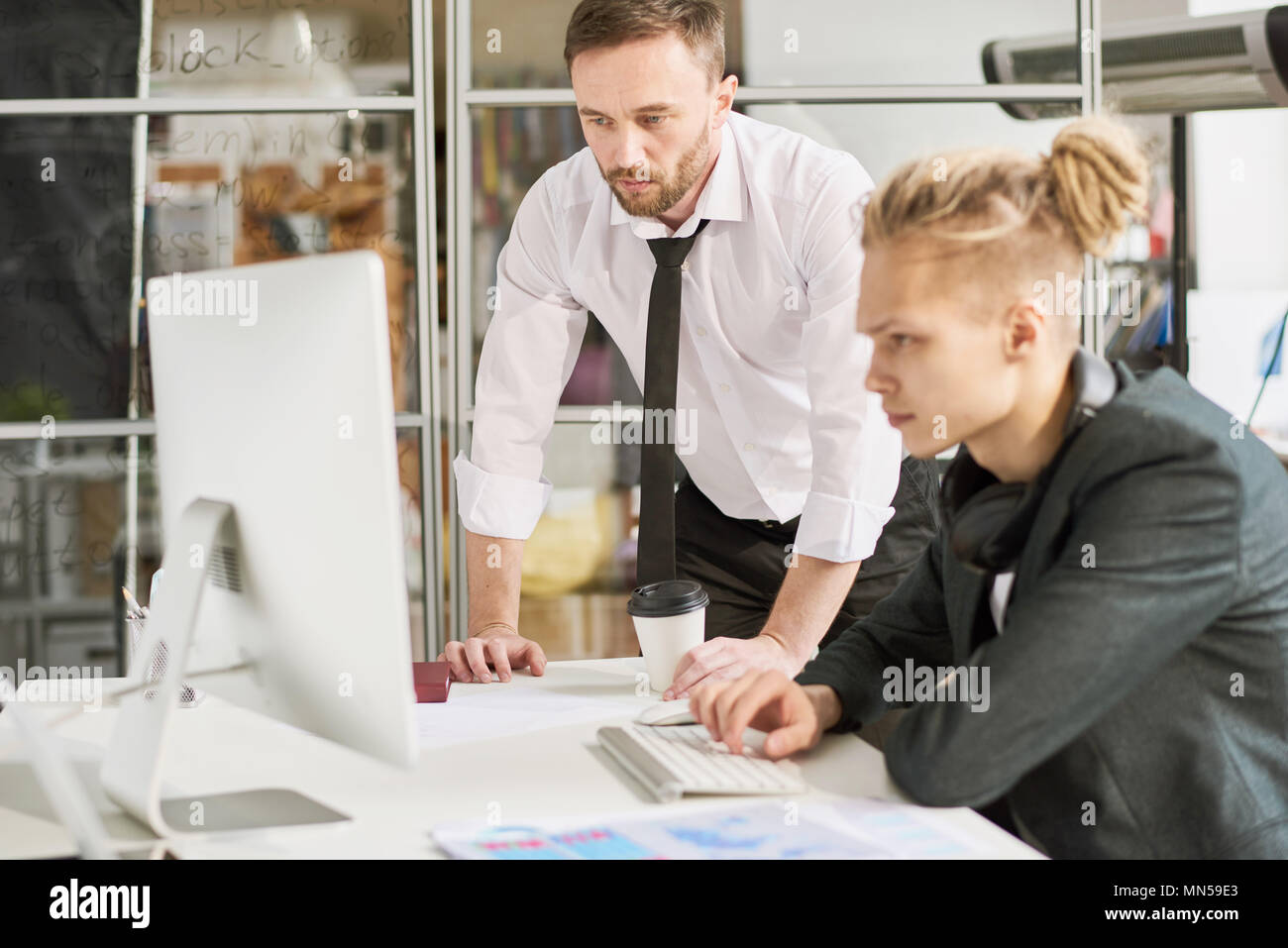 Portrait of handsome bearded businessman leaning over desk discussing ...