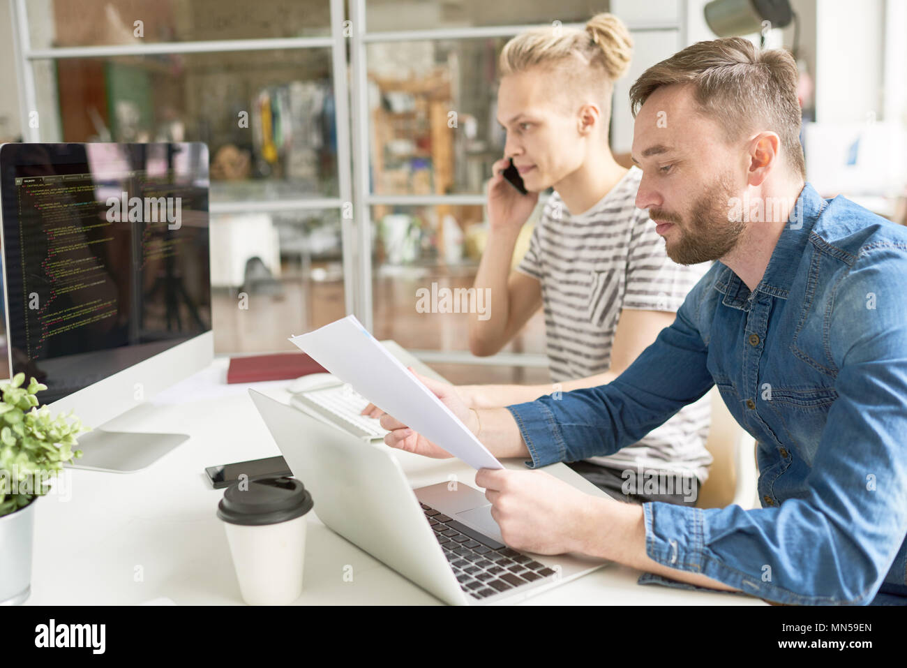 Side view portrait of two handsome young men in casual wear sitting at ...