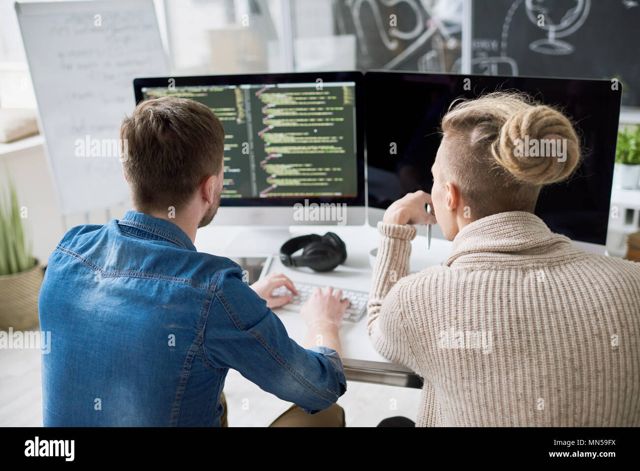 Back view portrait of two contemporary program developers writing code ...