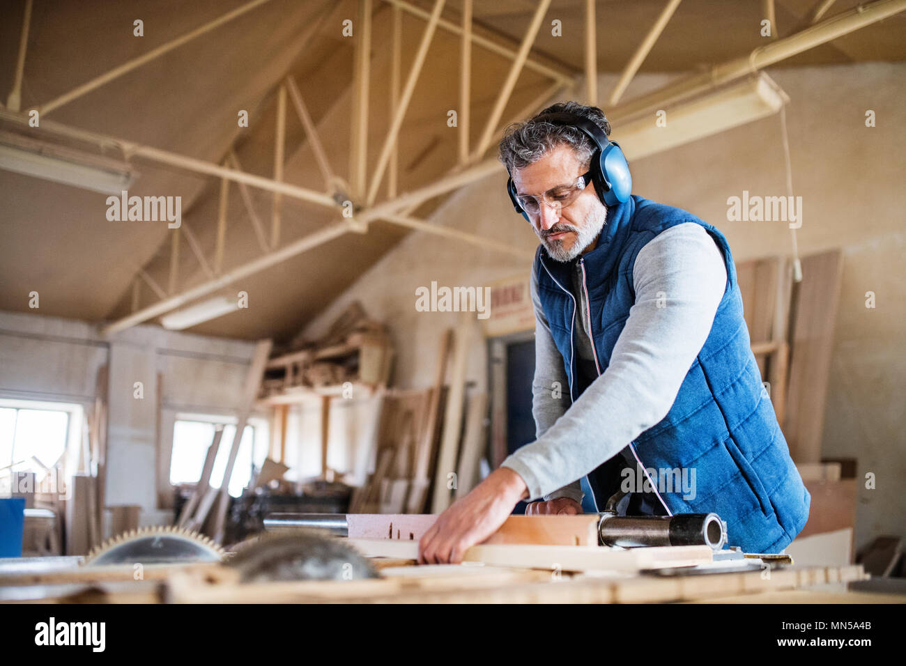 A mature man worker in the carpentry workshop, working with wood Stock ...