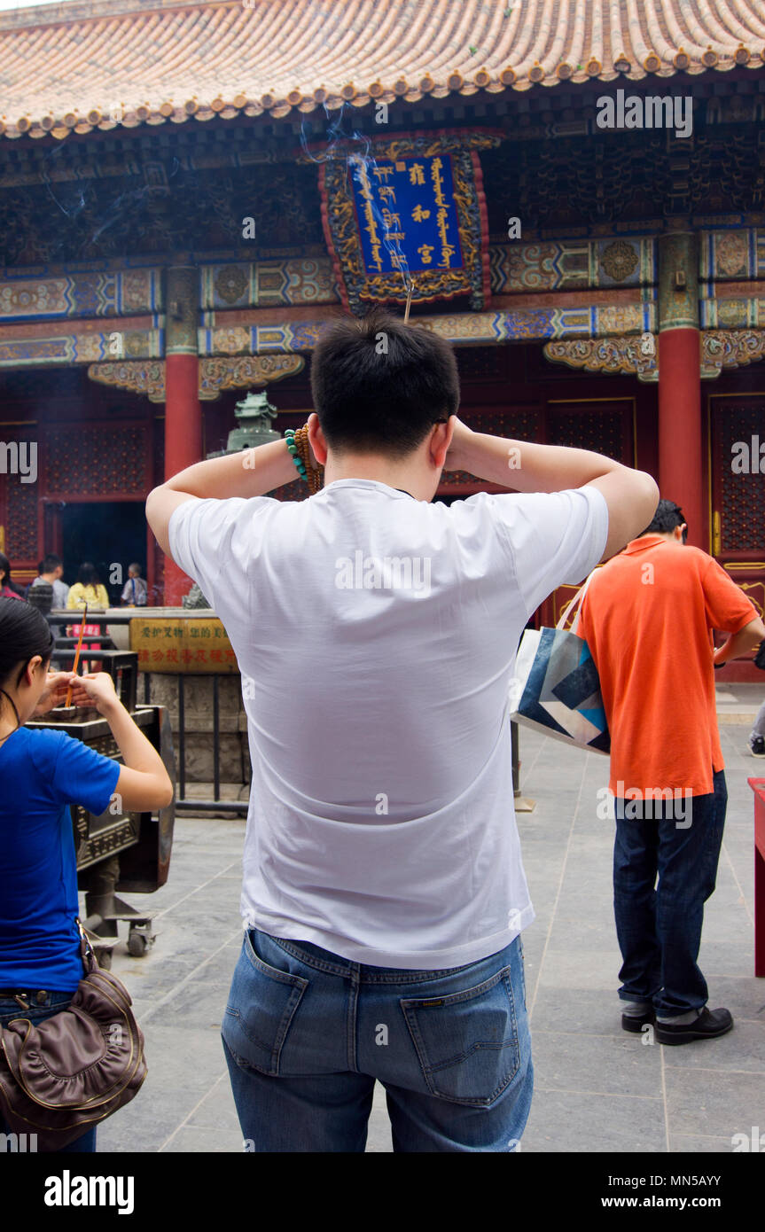 Chinese man praying with incense sticks at a shrine at the historic ...