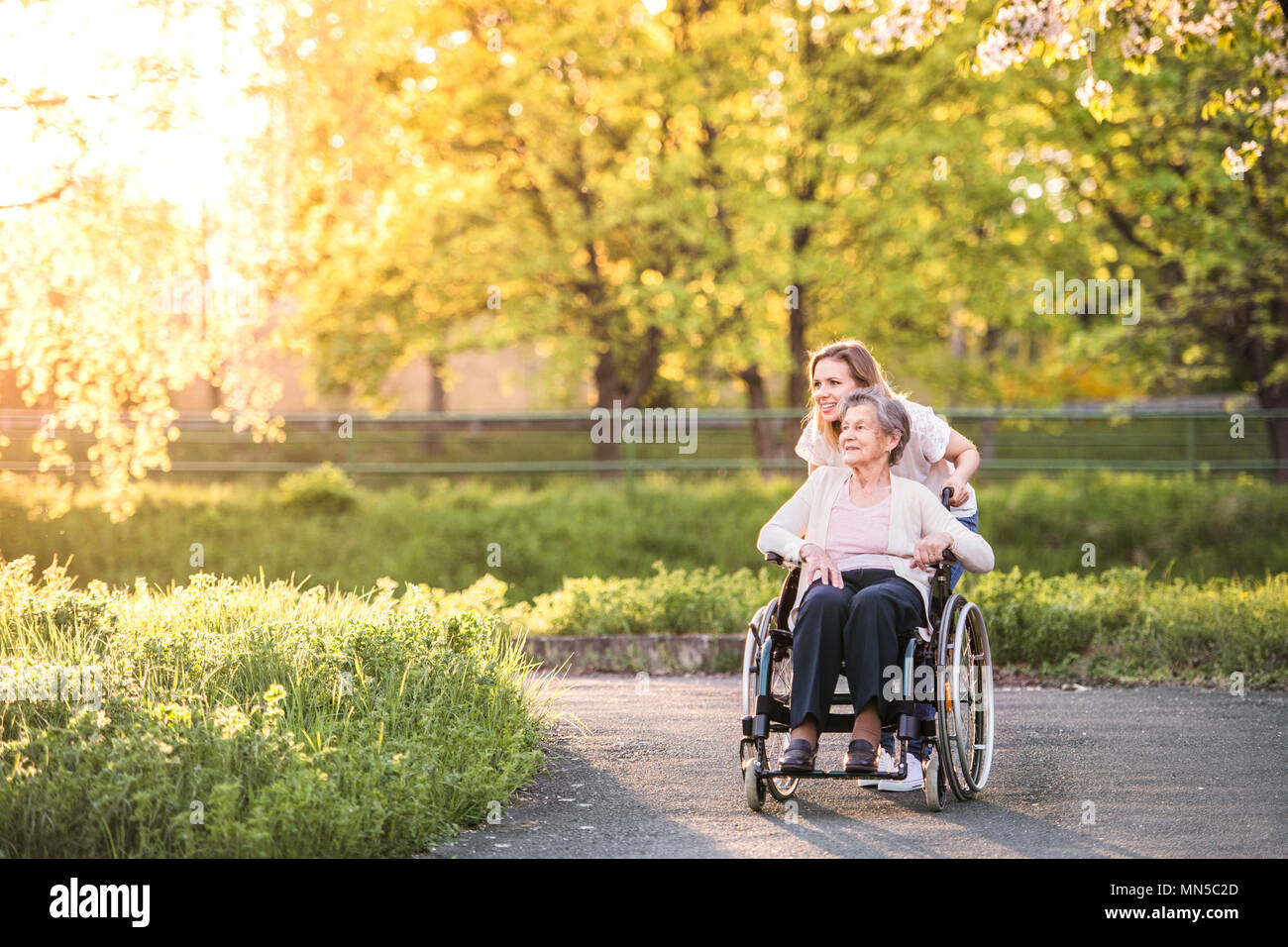 Elderly grandmother in wheelchair with an adult granddaughter outside ...