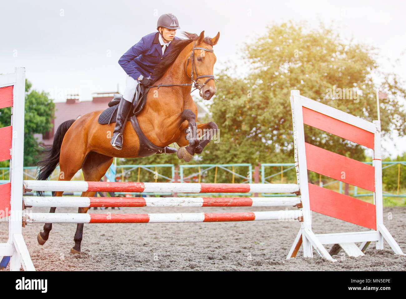 Young rider man jumping on horse over obstacle on show jumping ...
