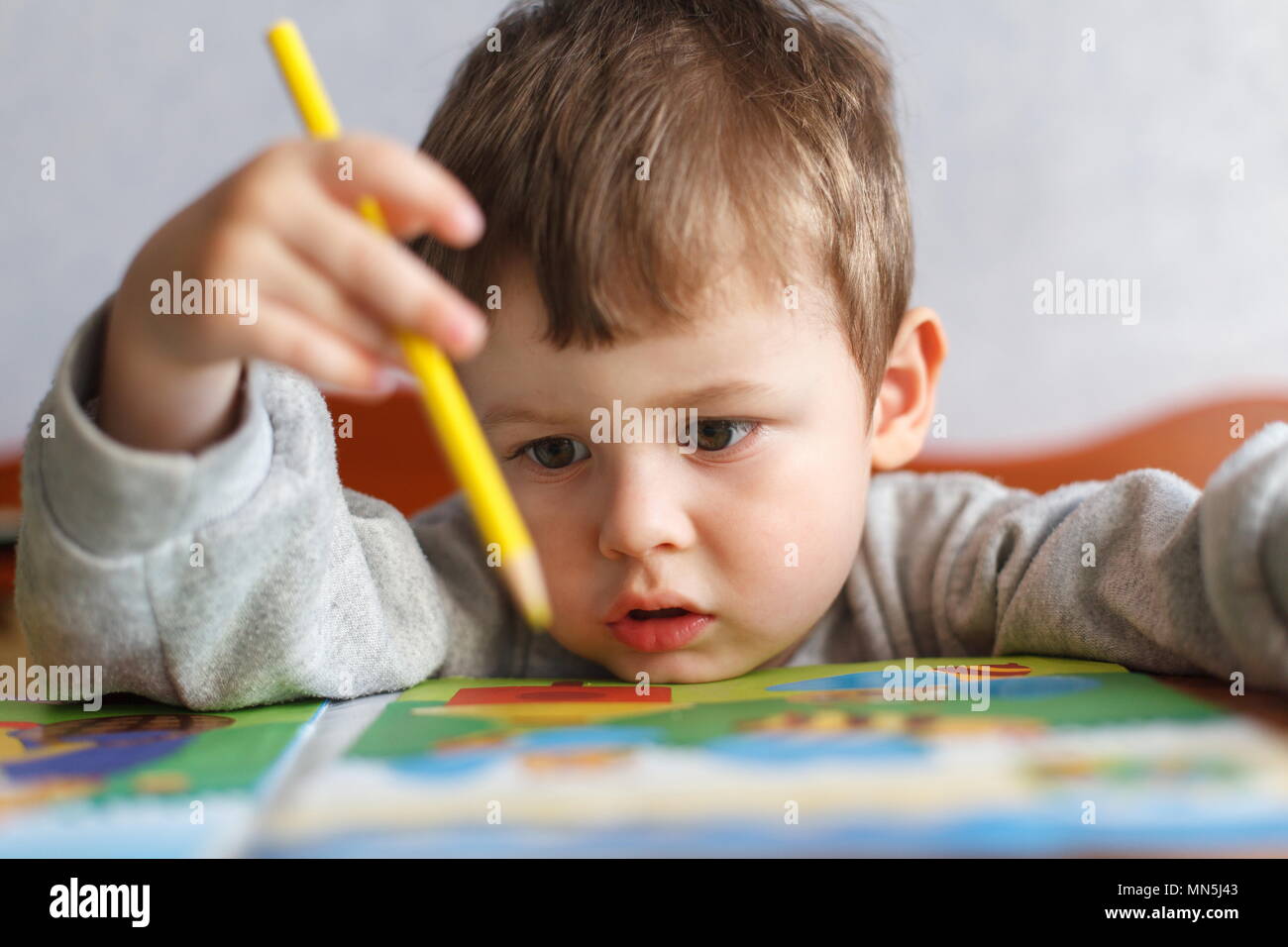 Little boy drawing with color pencils. Cute boy sitting at table and ...