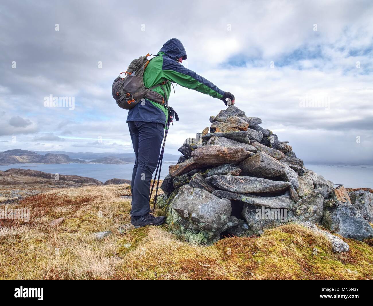 Stony pyramid on rocky peak. Mountain peak rising on small island in ...