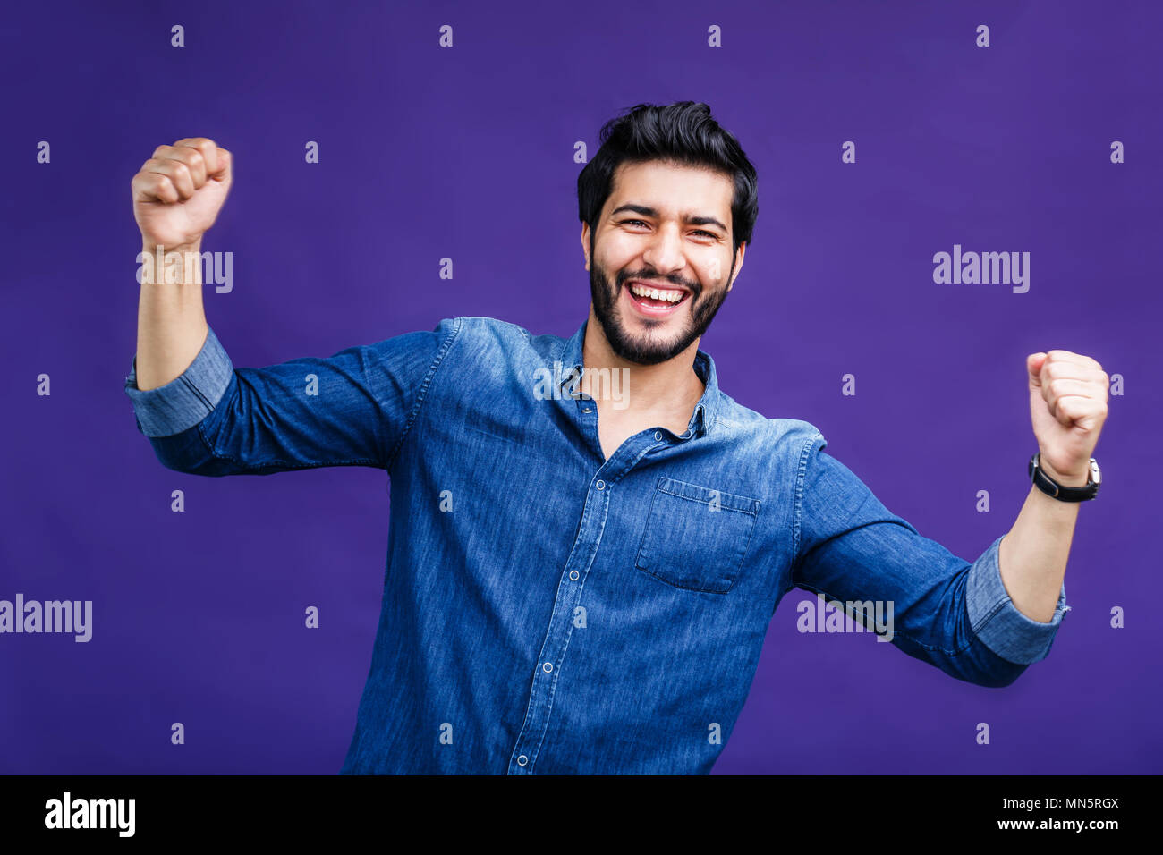 Portrait of happy successful man dressed in denim shirt on purple ...