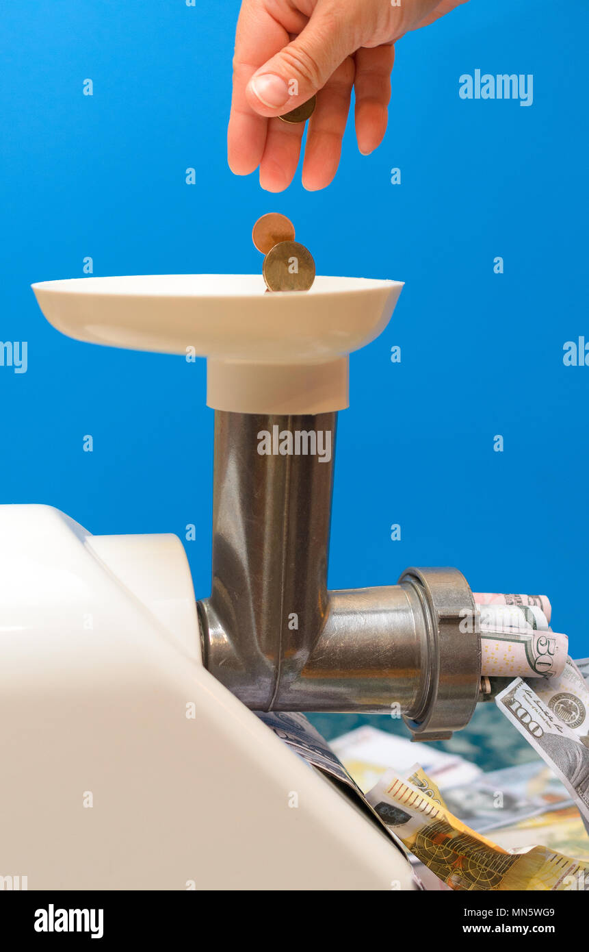 Money passes through a meat grinder. Blue background Stock Photo - Alamy