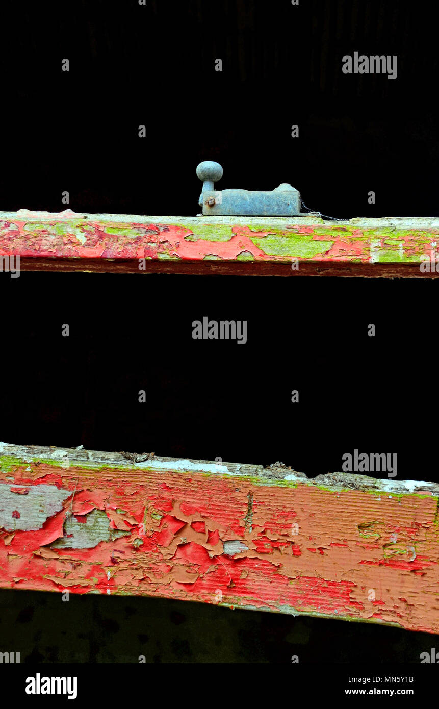 section of a derelict window frame with crumbling peeling red paint and ...