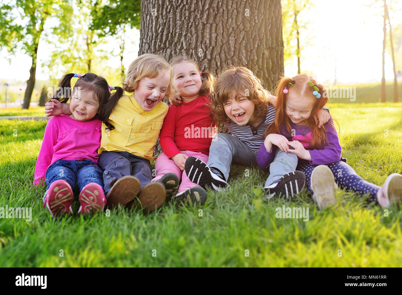 a group of small children in colorful clothes embracing sitting on the ...