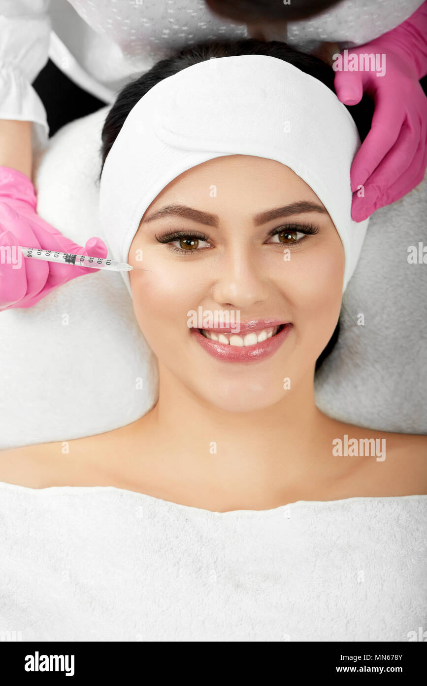 Close up of irl lying during cosmetological lips enlargment process ...