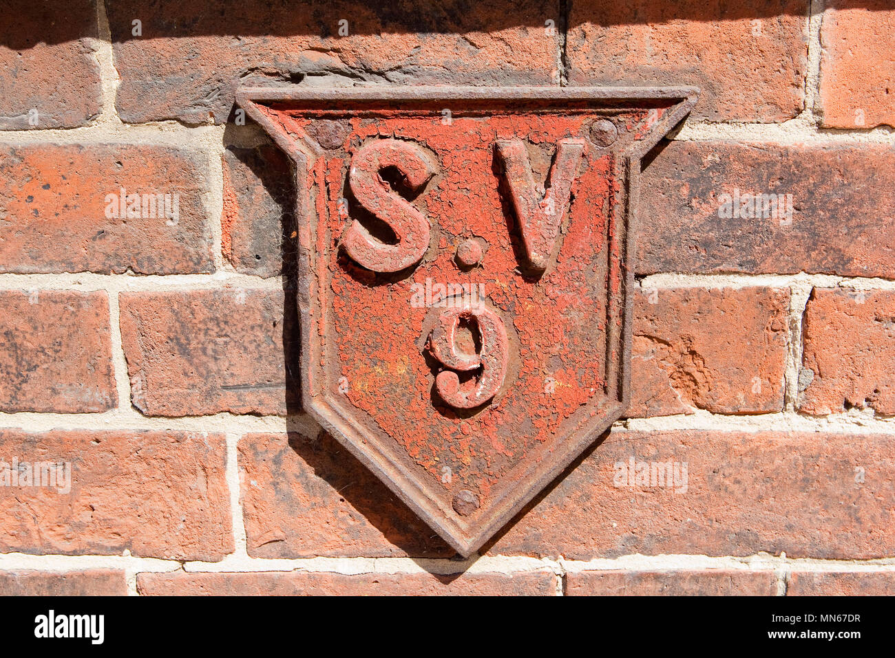 Old weathered red metal services point sign in a shield shape on a ...