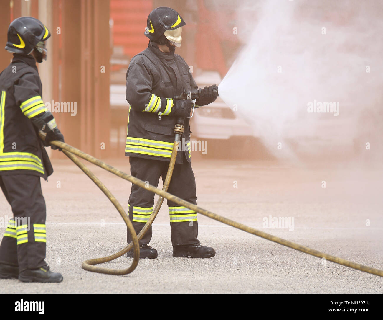 two firemen with the mask extinguish a fire with white foam Stock Photo ...