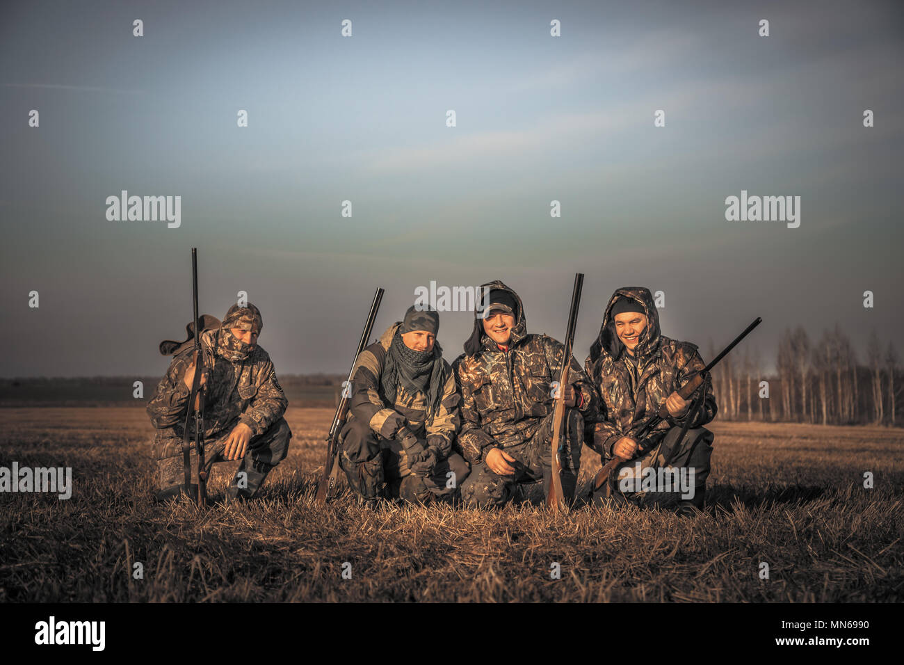 Men hunters group team portrait in rural field posing together against ...